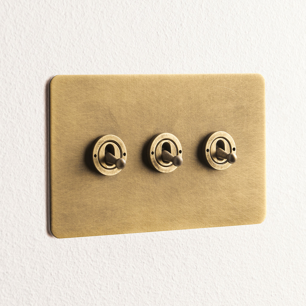 Lucian three gang 2 way toggle switch in aged brass